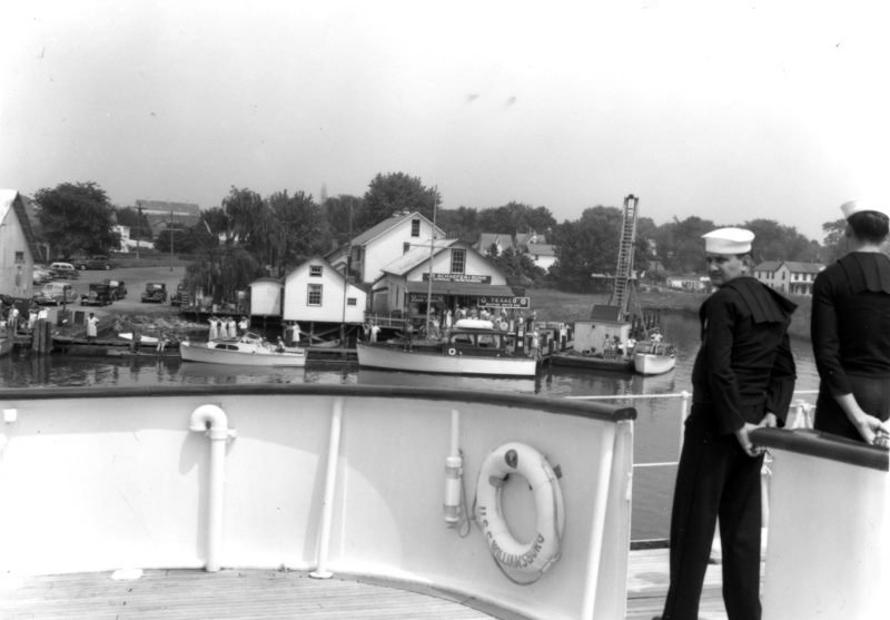Two sailors on board the Williamsburg view buildings on the shore of an ...
