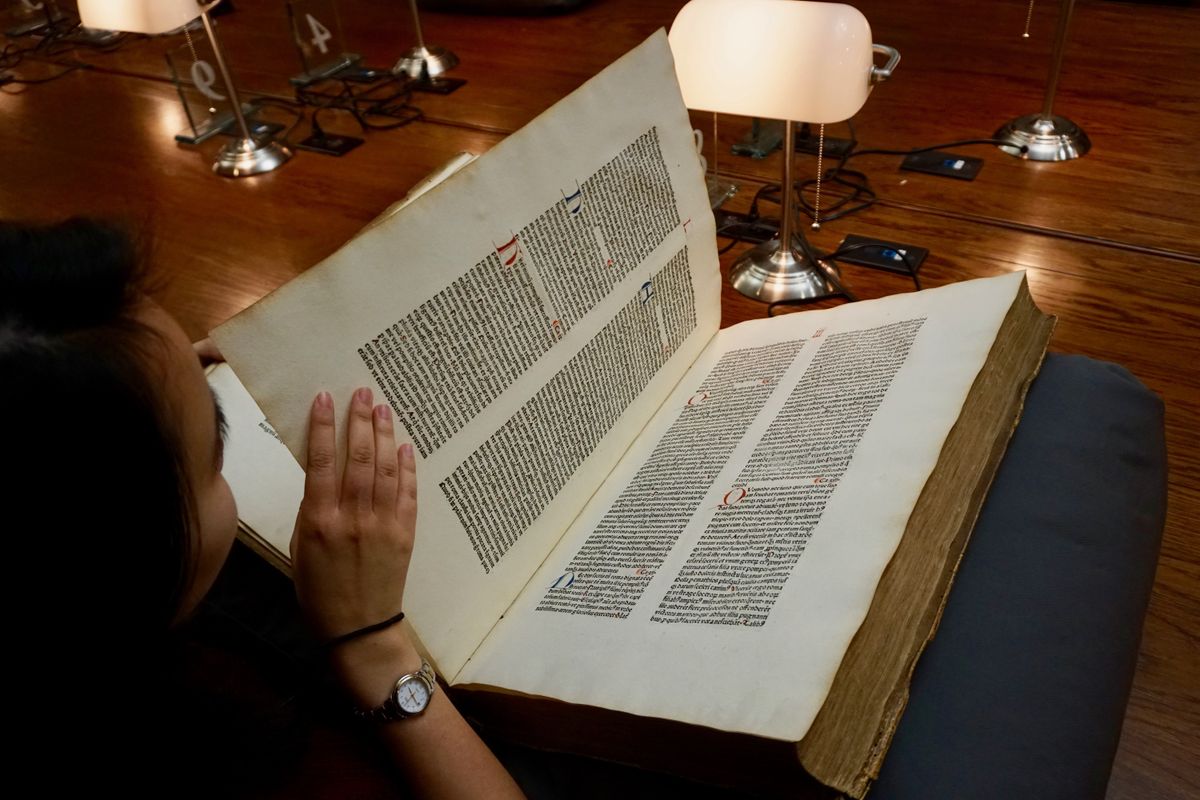 Photo | Student reading old book in special collections reading room | UCLA