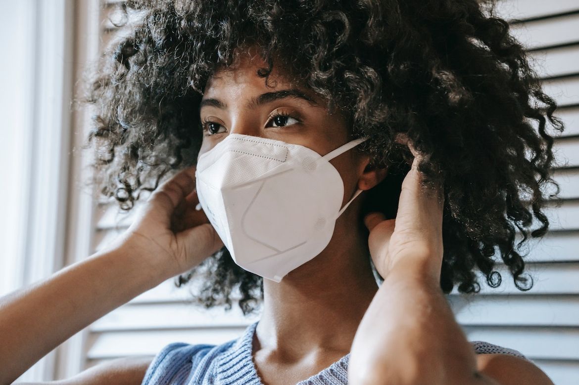 Photo | Woman putting on face covering | UCLA
