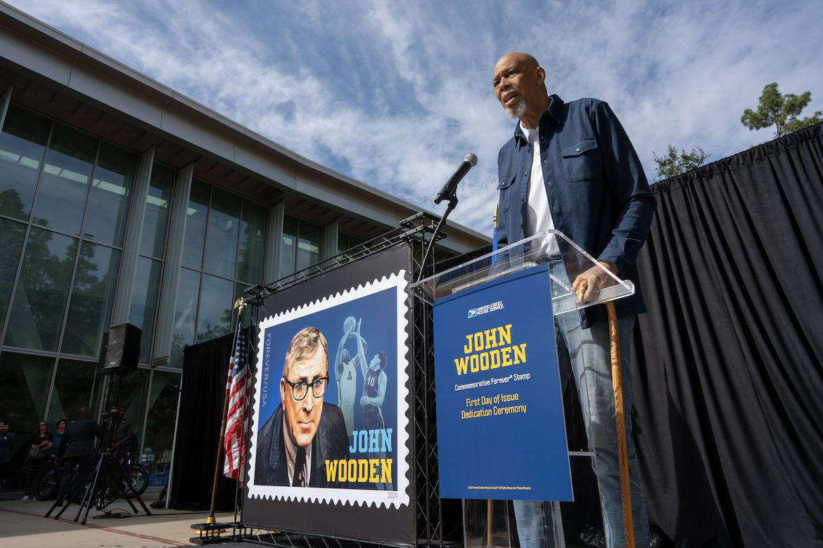 Photo | Kareem Abdul-Jabbar speaking at podium next to enlarged John ...
