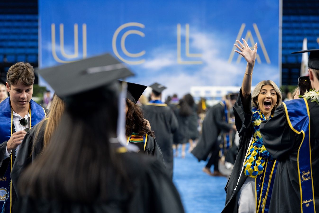 Photo | Students celebrate commencement with UCLA sign in background | UCLA