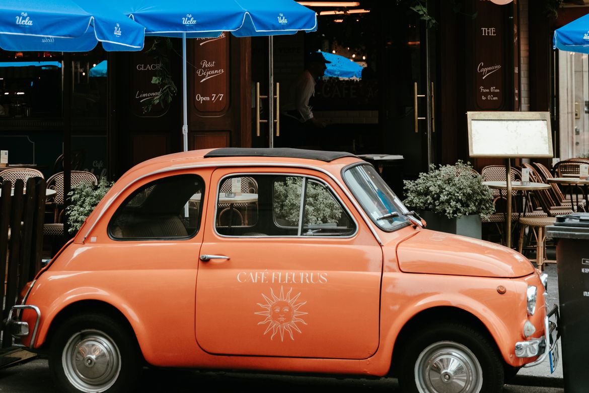 Photo | Orange vintage car with Café Fleurus logo on passenger door | UCLA