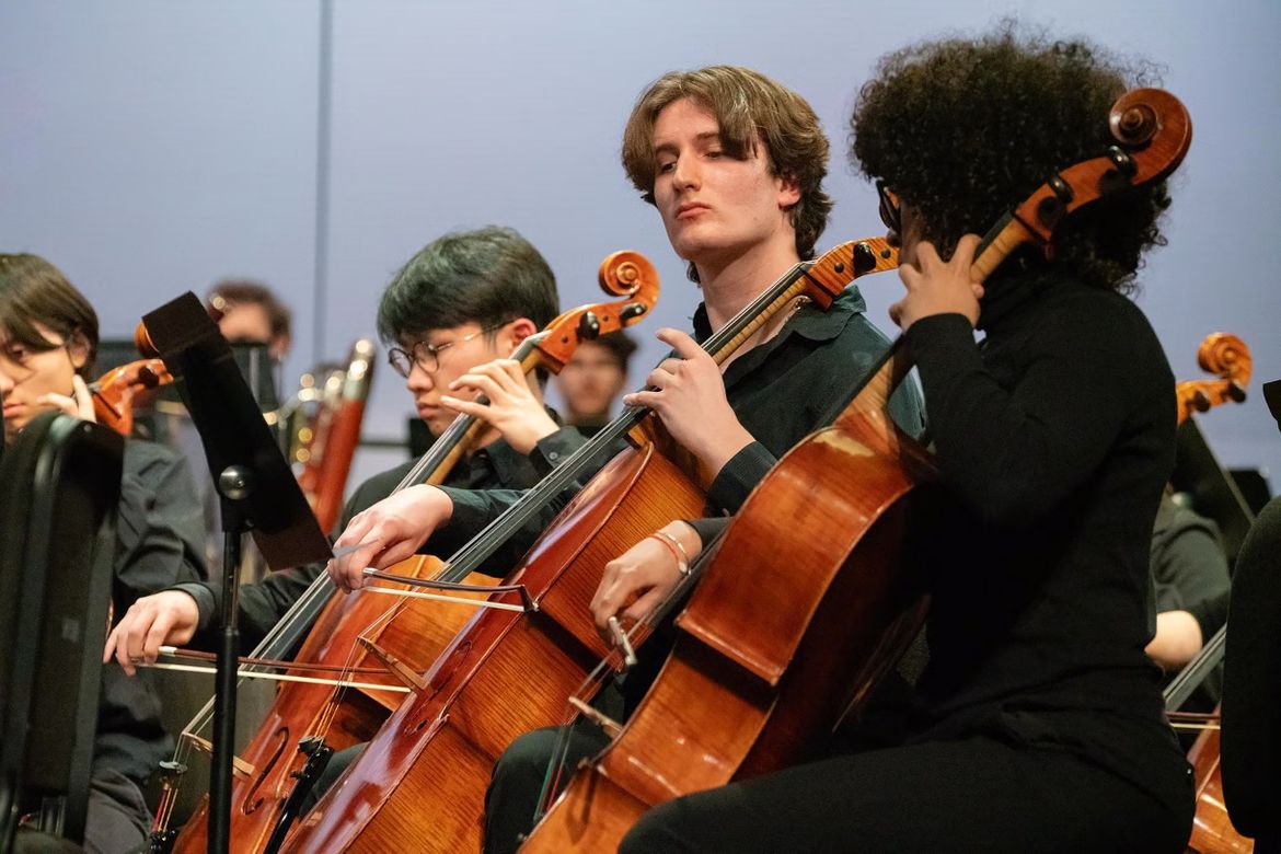 Photo | Three orchestra students in black playing the cello | UCLA