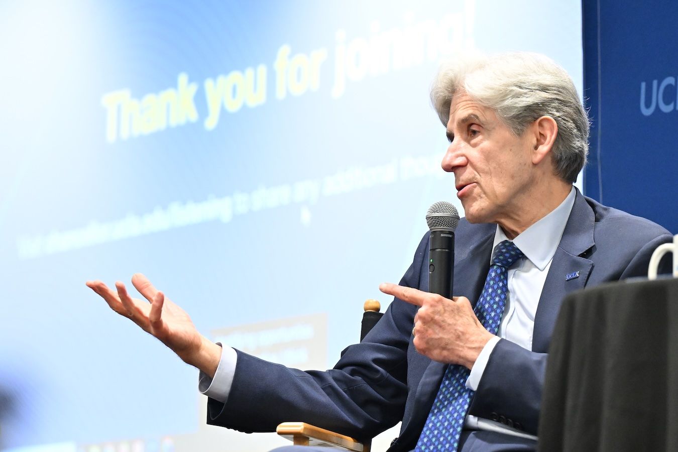 Photo | Julio Frenk speaking into microphone with arm upraised | UCLA