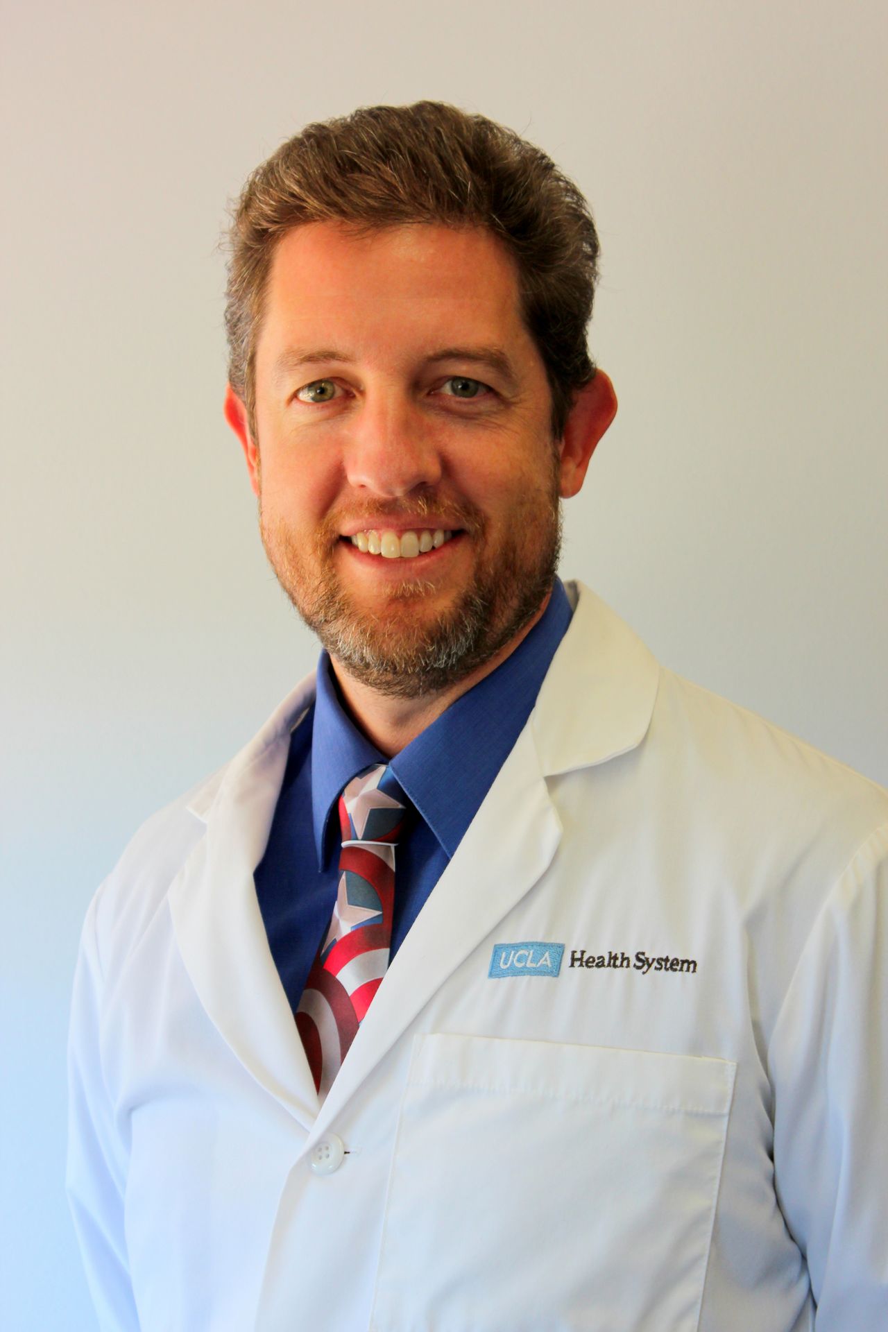 Photo | Headshot of Dr. Steven Mittelman smiling in a white UCLA Health ...