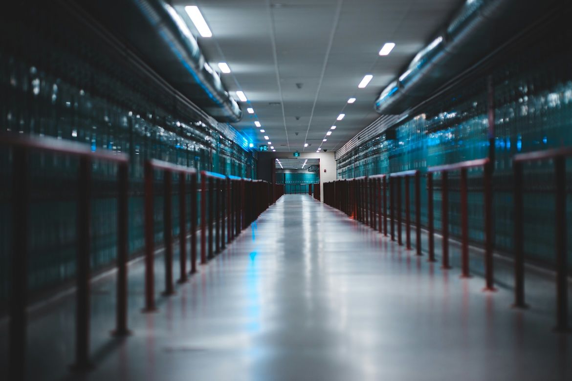 Photo | A long corridor of server racks in a data center, lit with blue ...