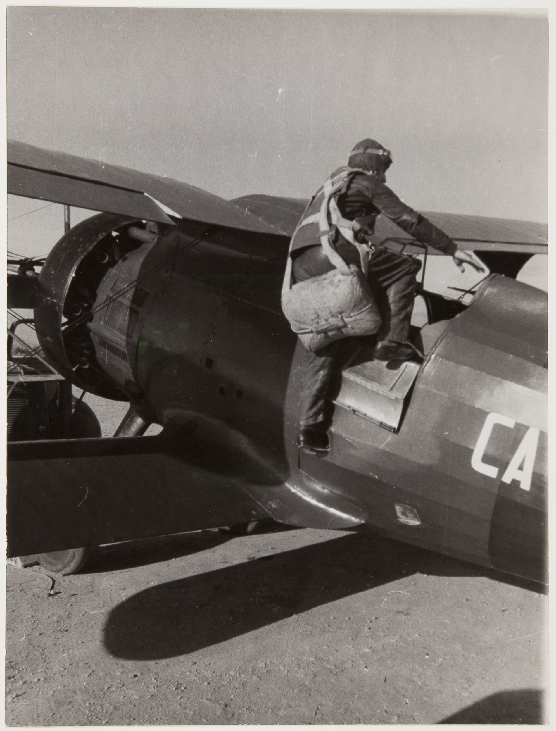 [Pilot climbing into plane, Spain] | International Center of Photography