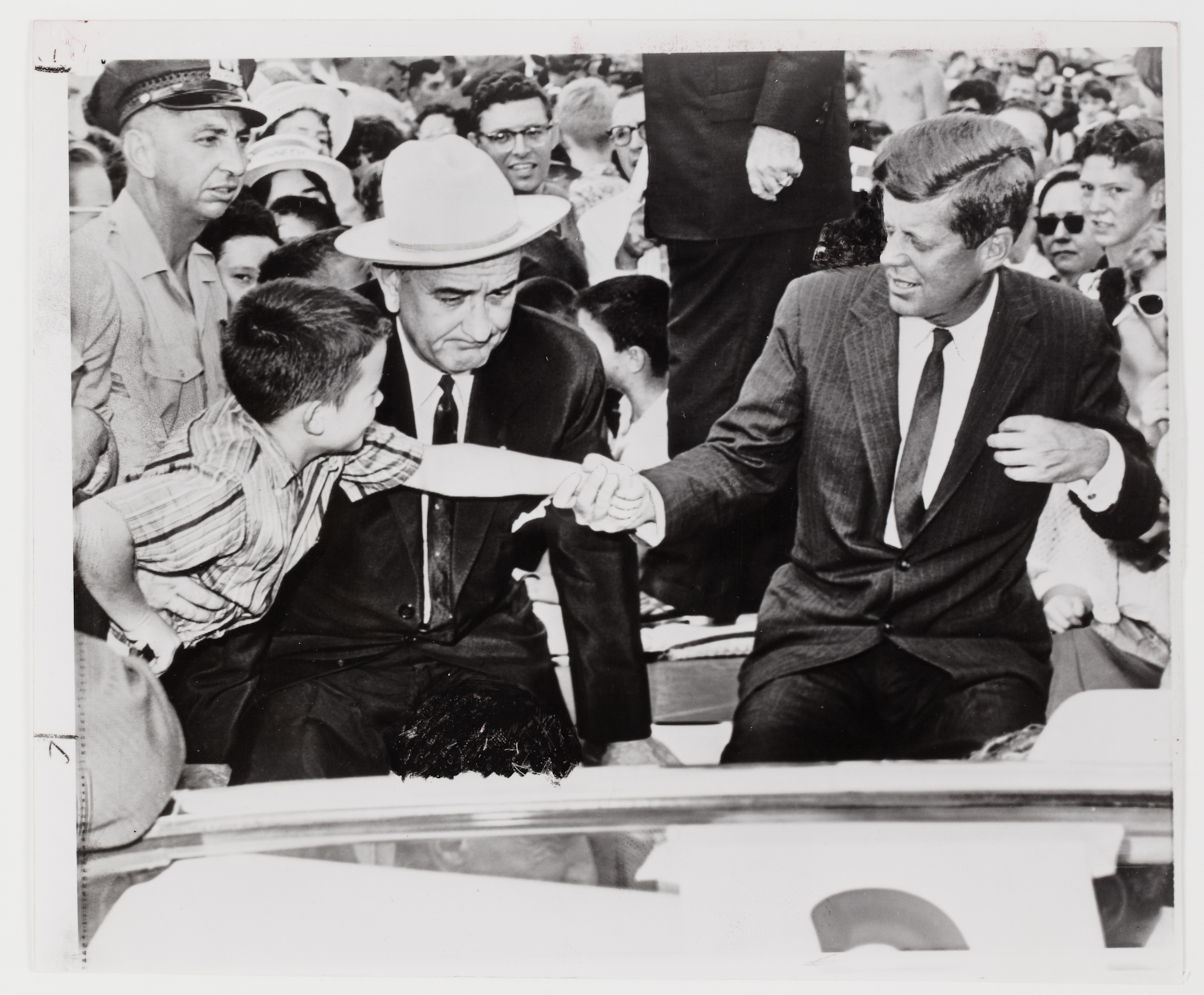[Senator John F. Kennedy shaking hands with a young boy while sitting ...