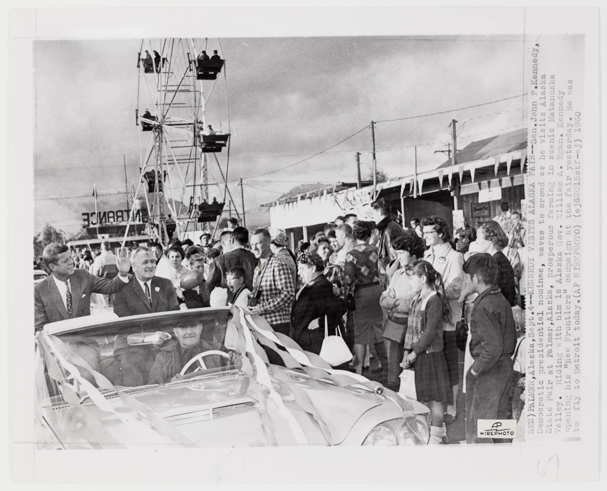 [Senator John F. Kennedy waving to the crowd while riding in a car with ...