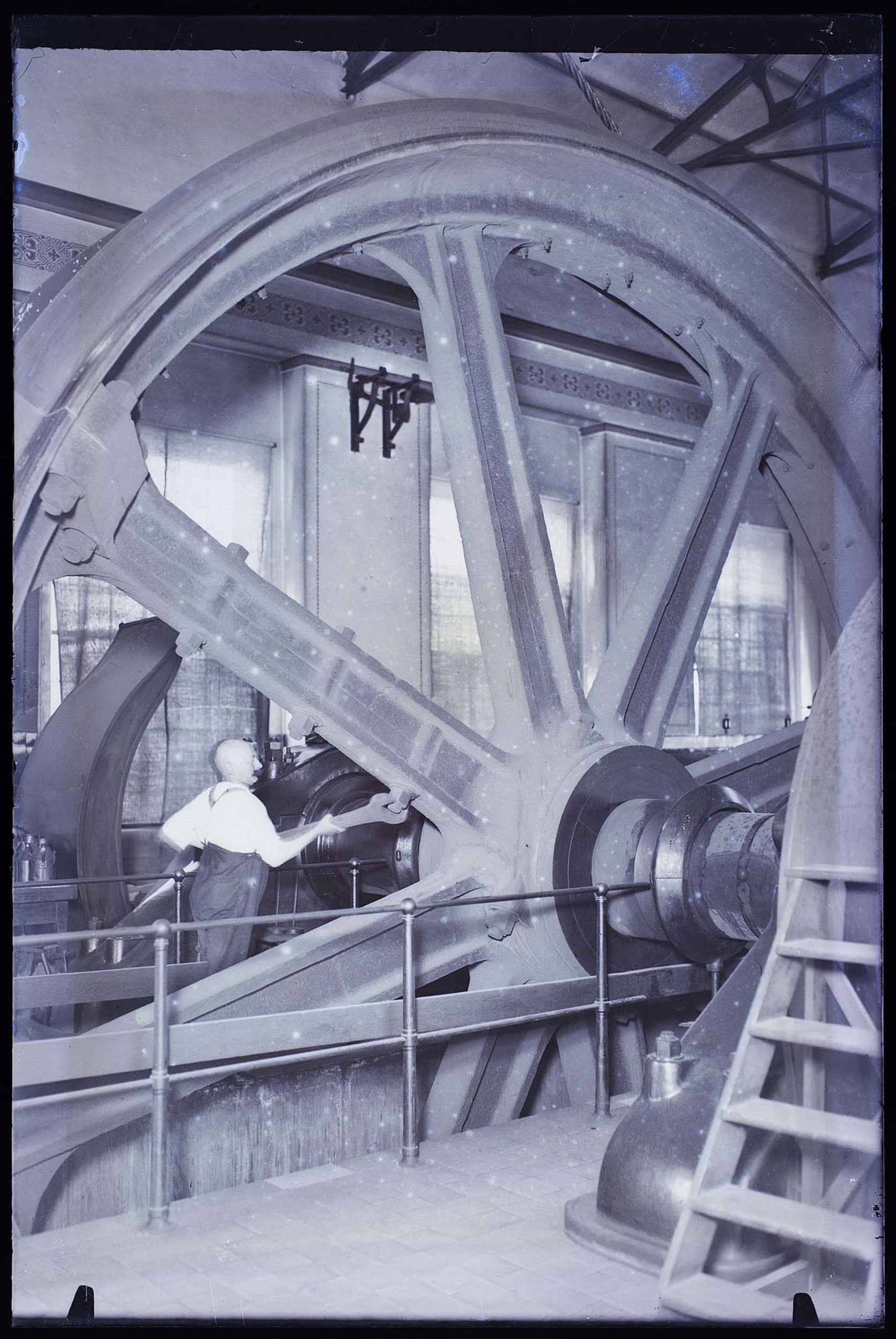 [Man adjusting bolt on giant wheel] | International Center of Photography