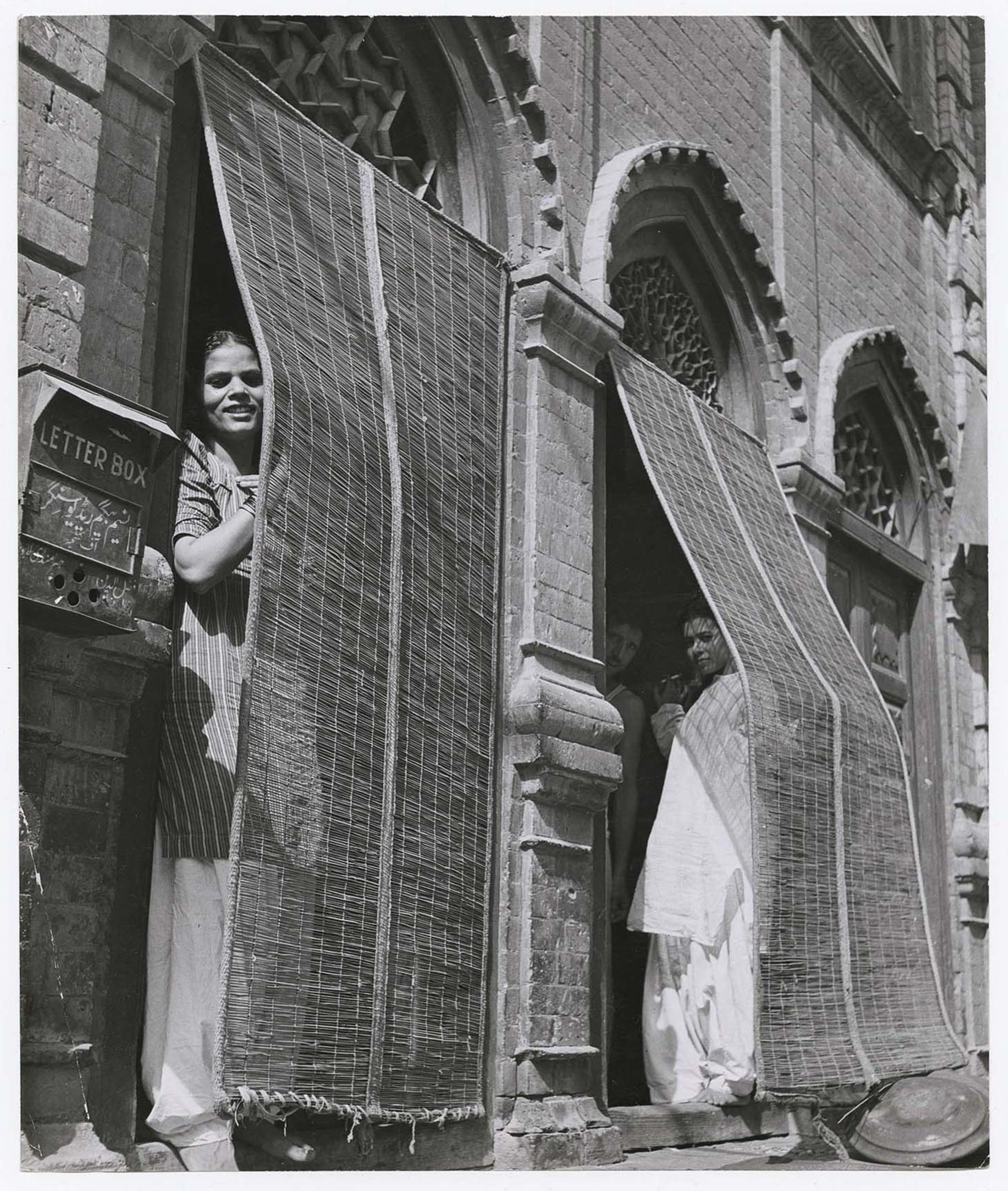 [Indian prostitutes peeking out from the doorways of their brothel ...