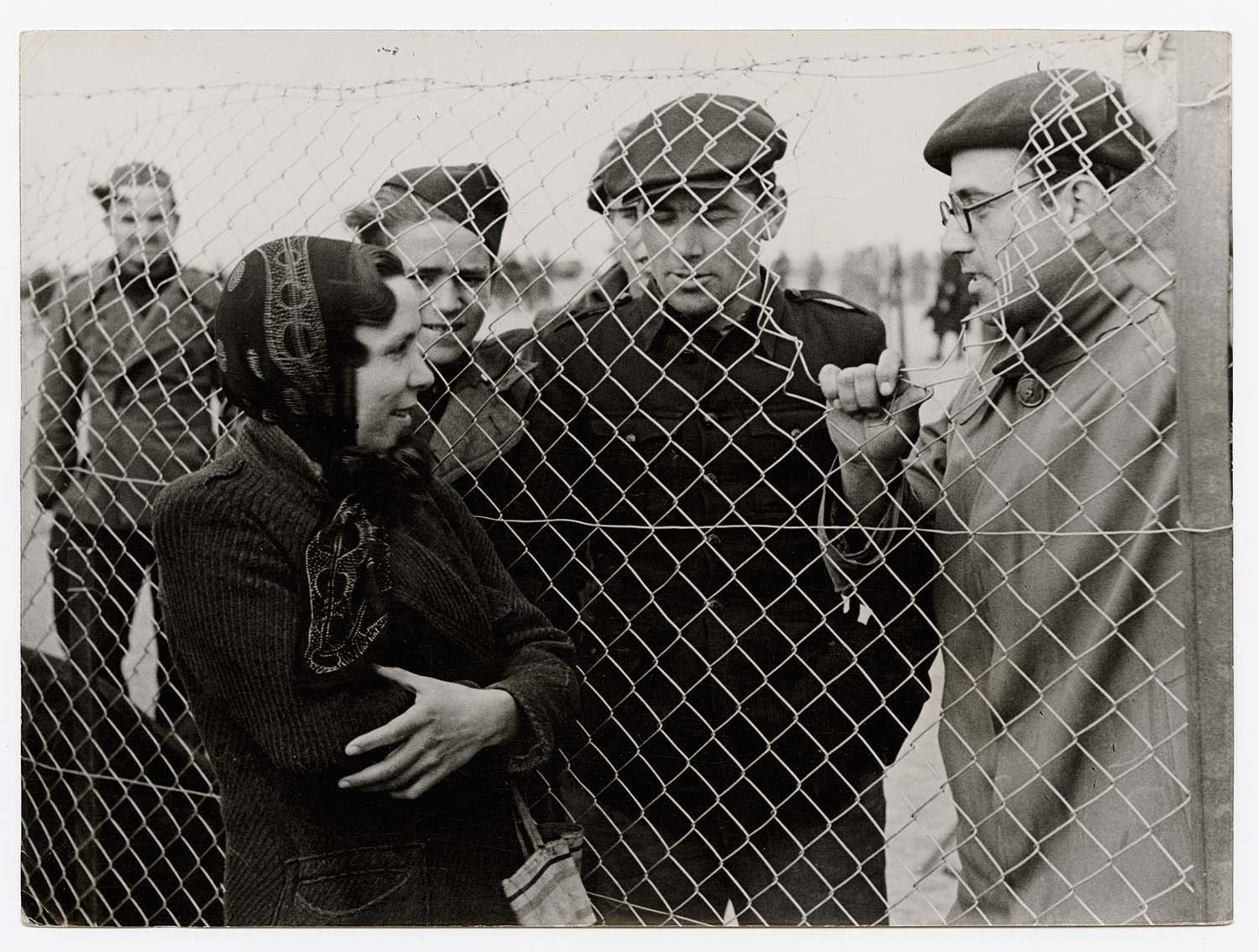 [Men talking to a young woman across a fence at a concentration camp ...