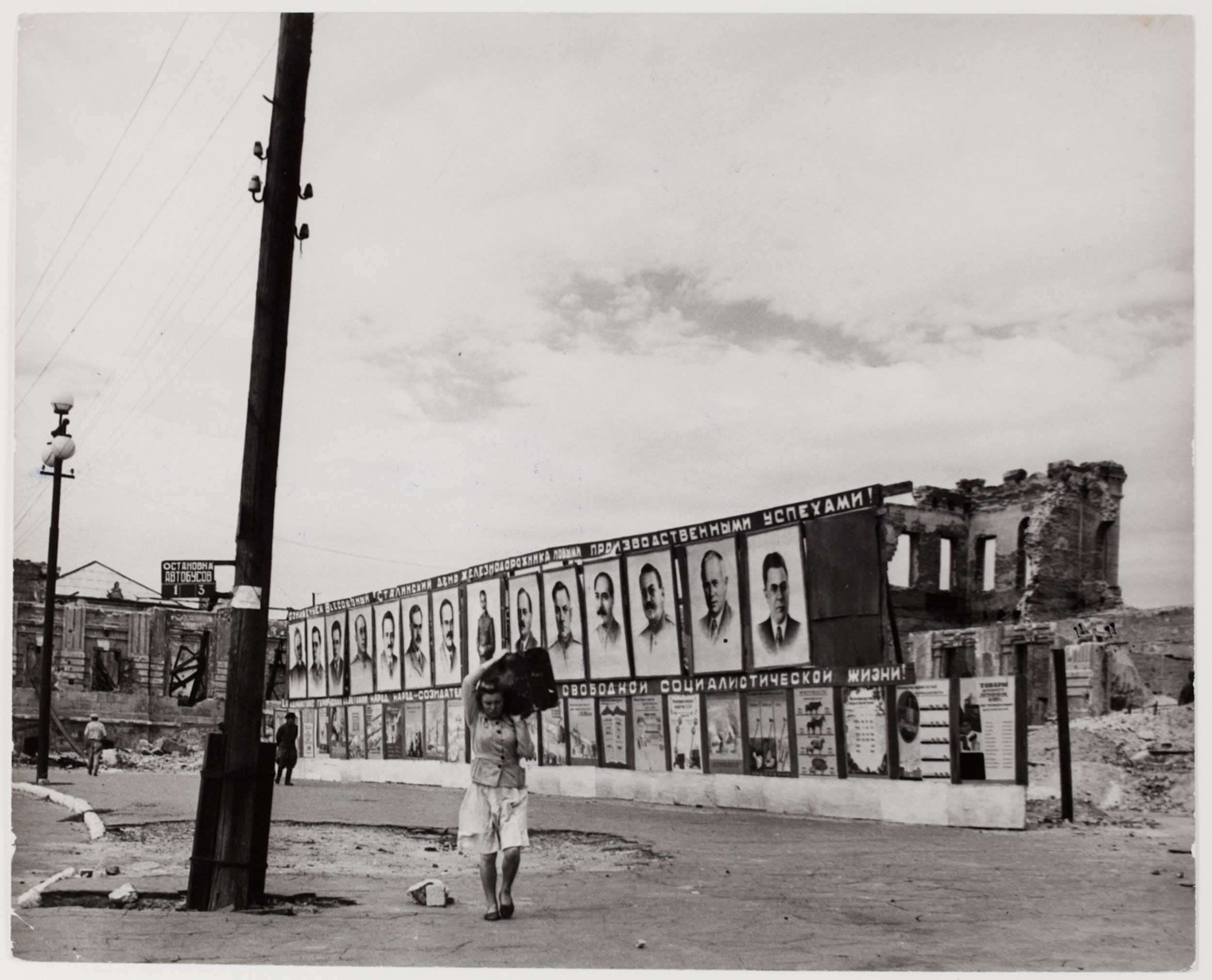 [Woman carrying case in front of huge sign depicting Stalin and other ...