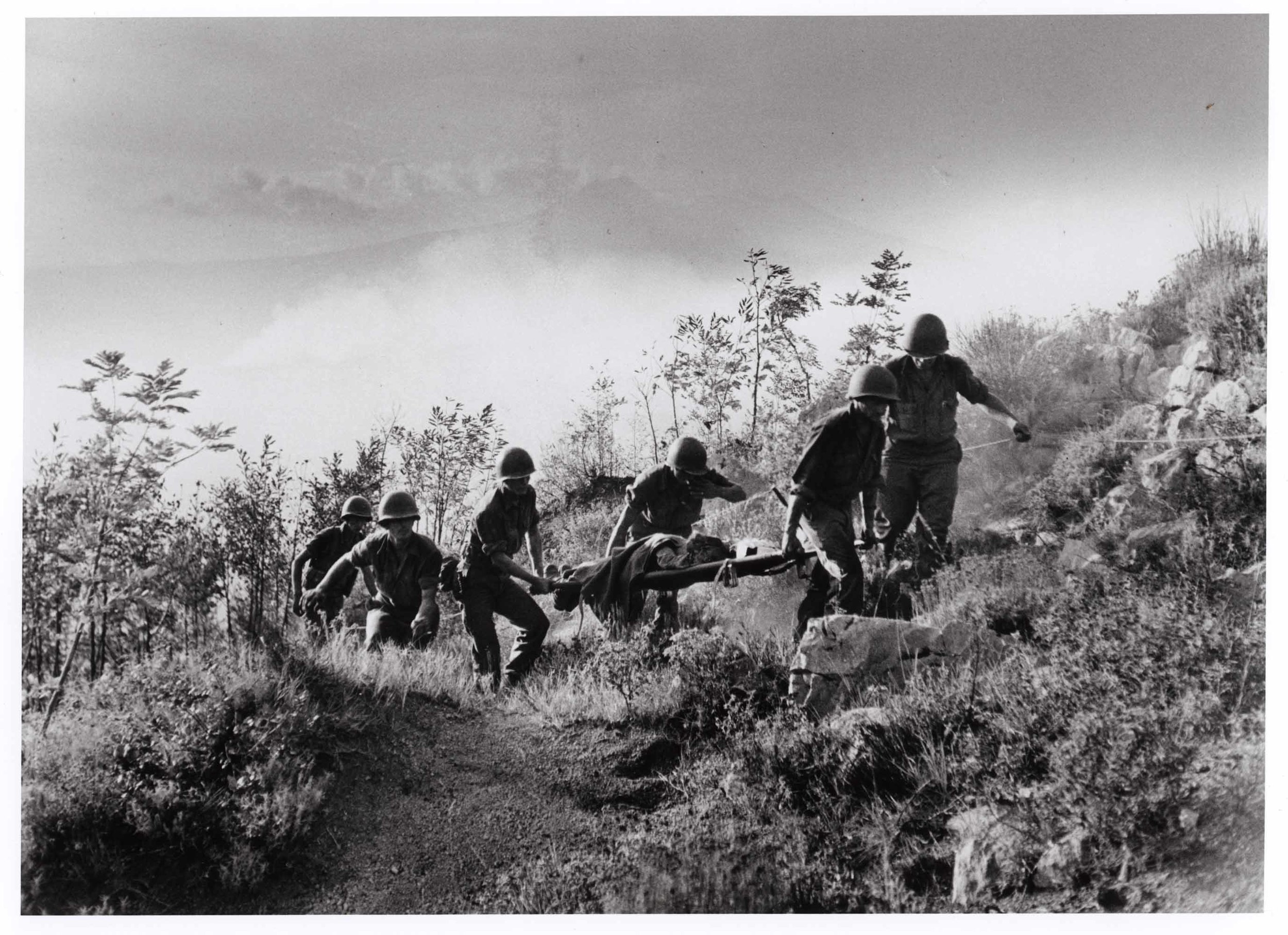 [American soldiers carrying wounded soldier on stretcher, along road to ...