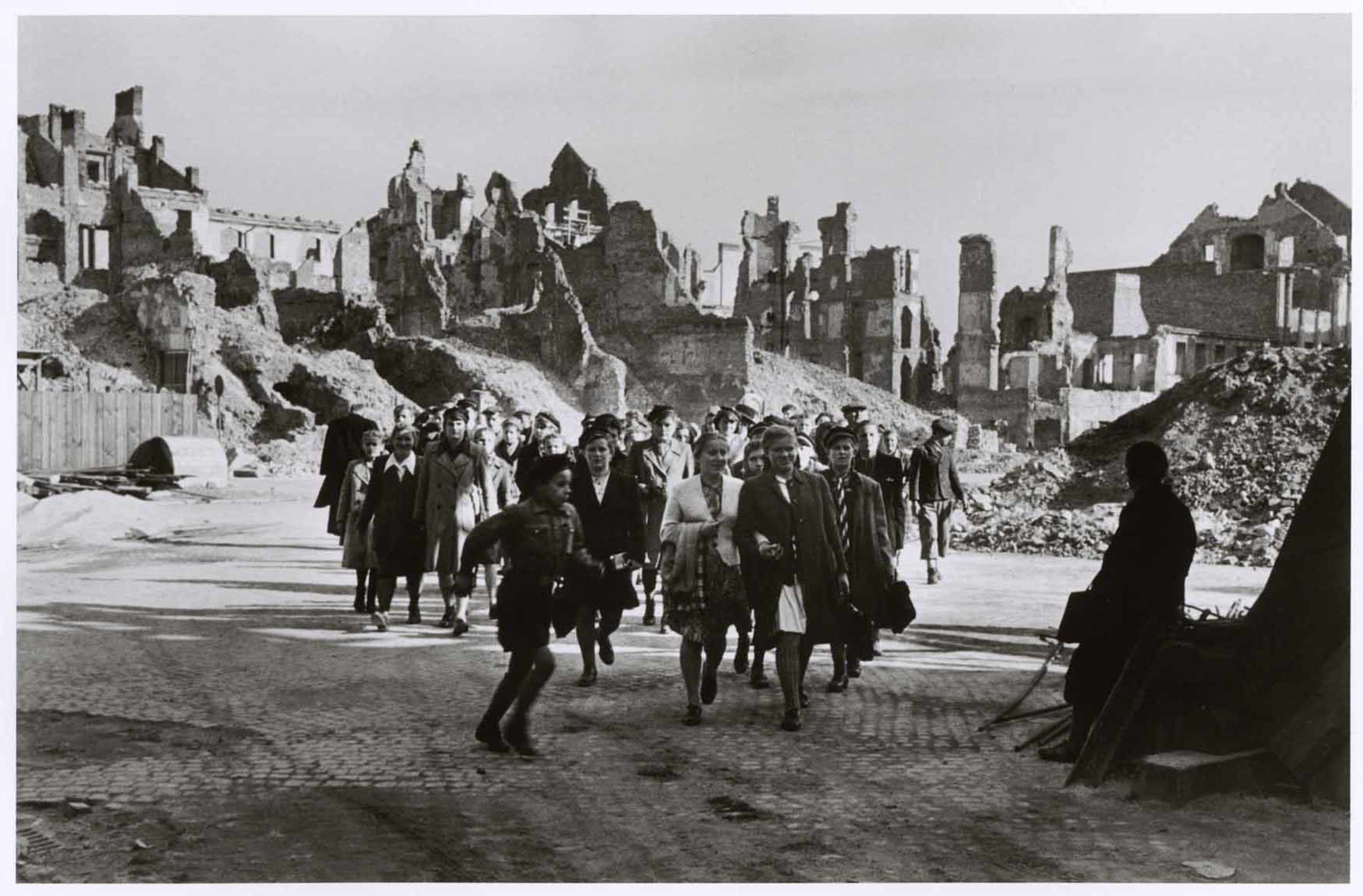 [Crowd of civilians walking through the ruins of Warsaw ...