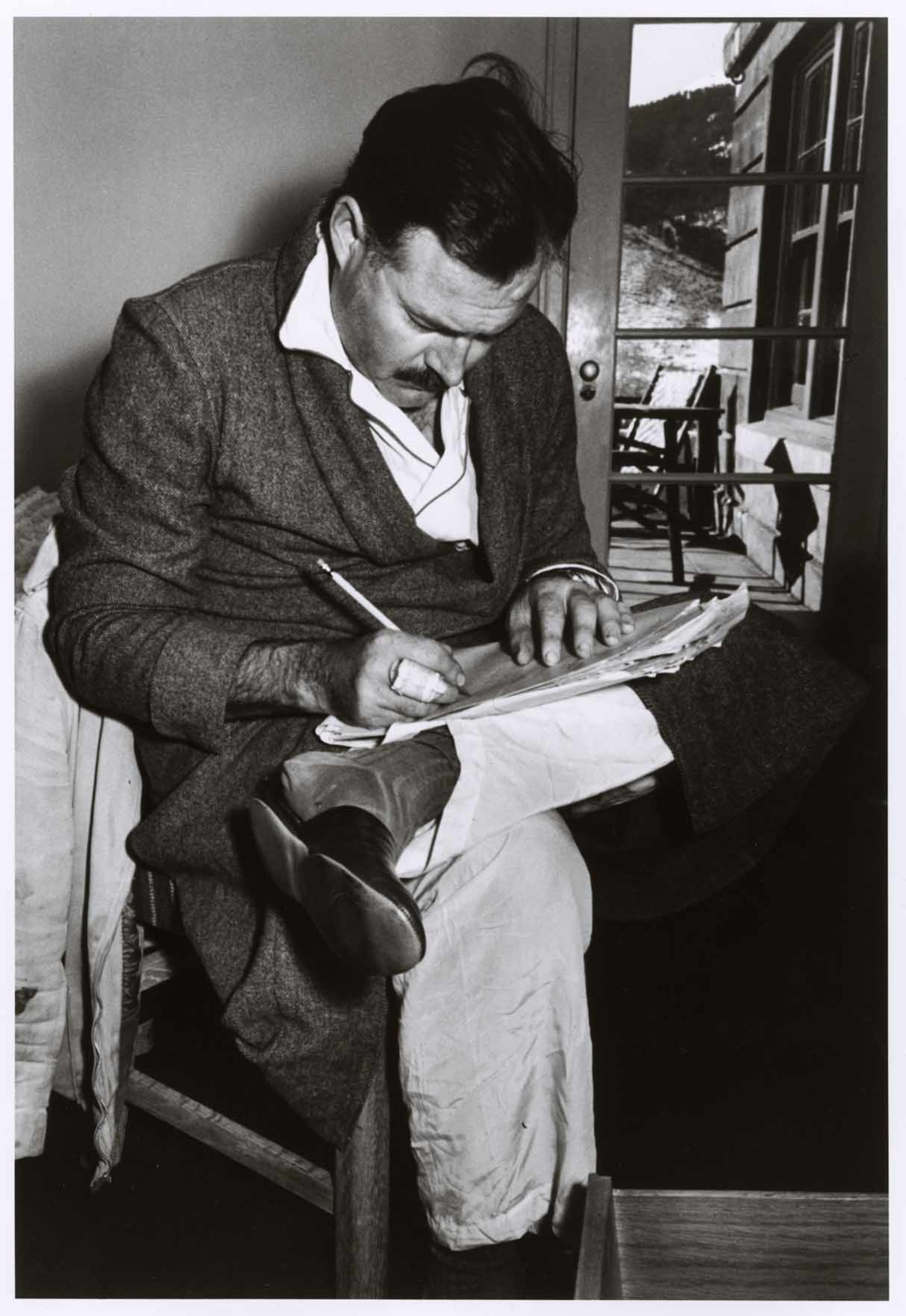 [Ernest Hemingway writing, wearing only his pajamas and bathrobe, Sun ...