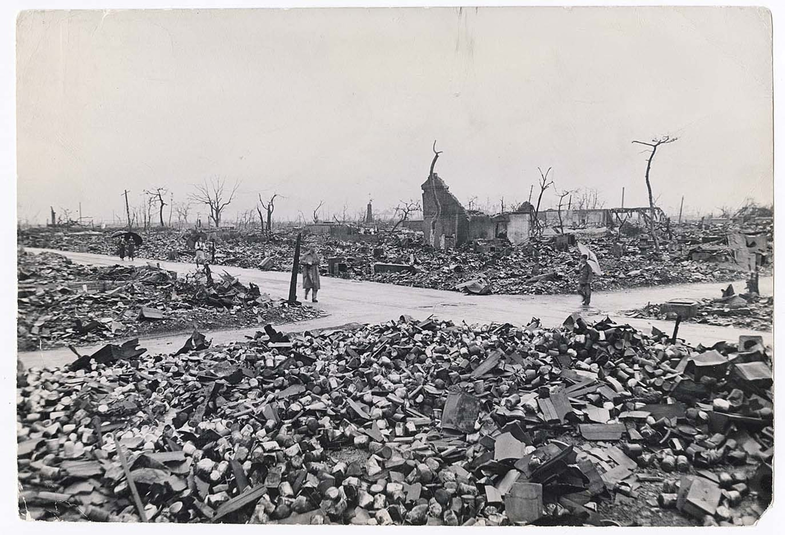 [Residents wander cleared streets bisecting the ruins of buildings ...