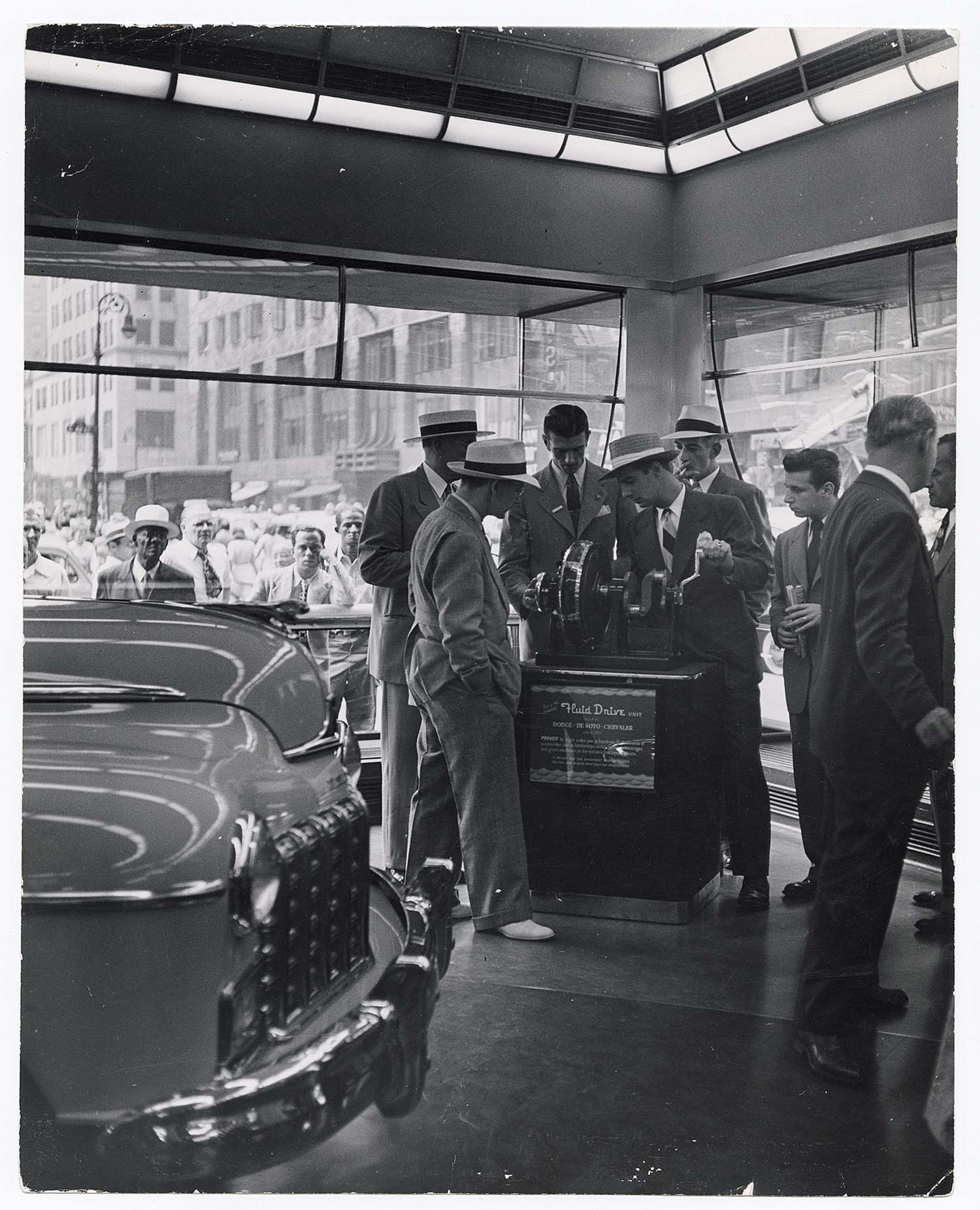 [Men examining a fluid drive unit on display in automobile showroom ...