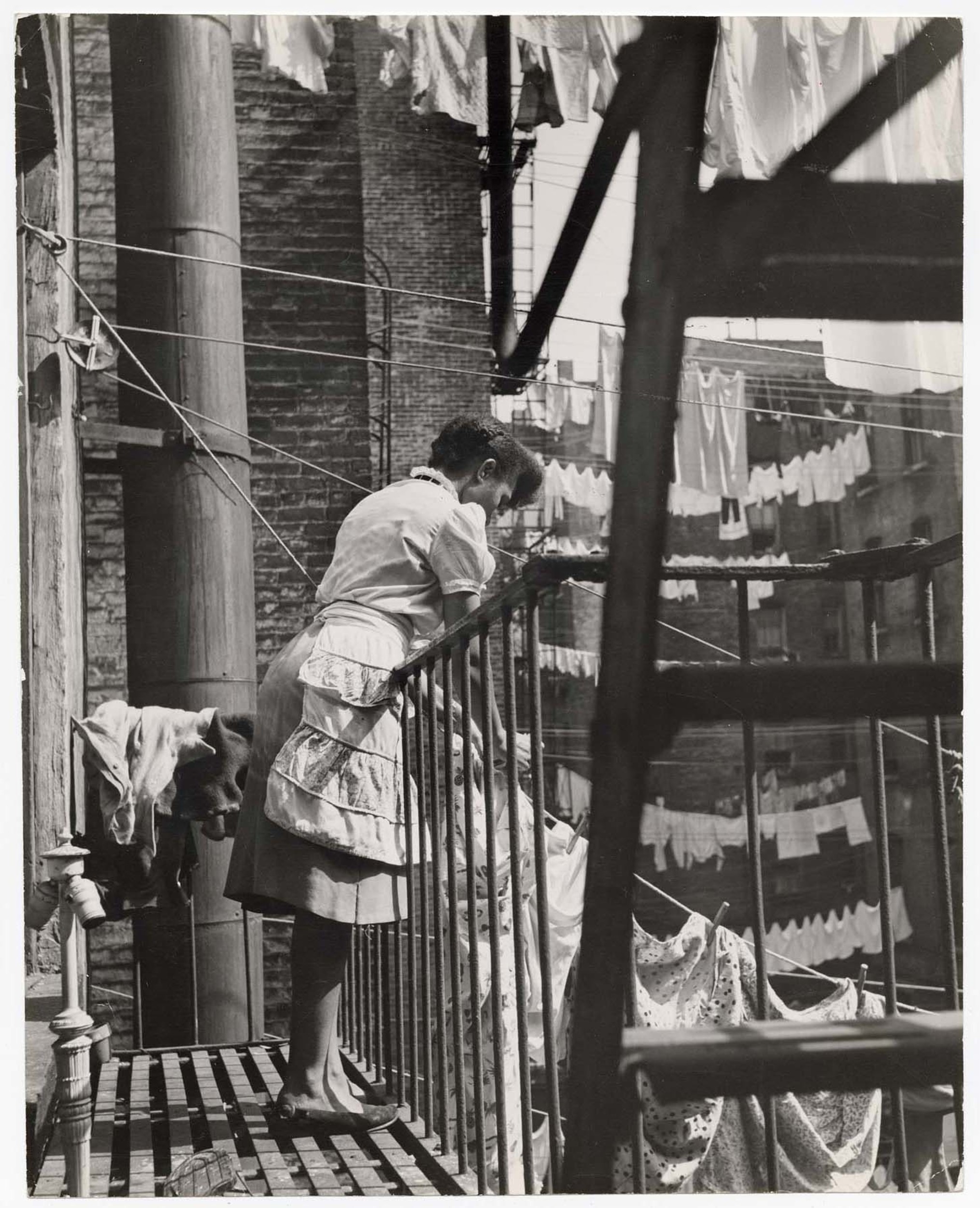 [Young woman on fire escape hanging laundry on clothesline strung ...