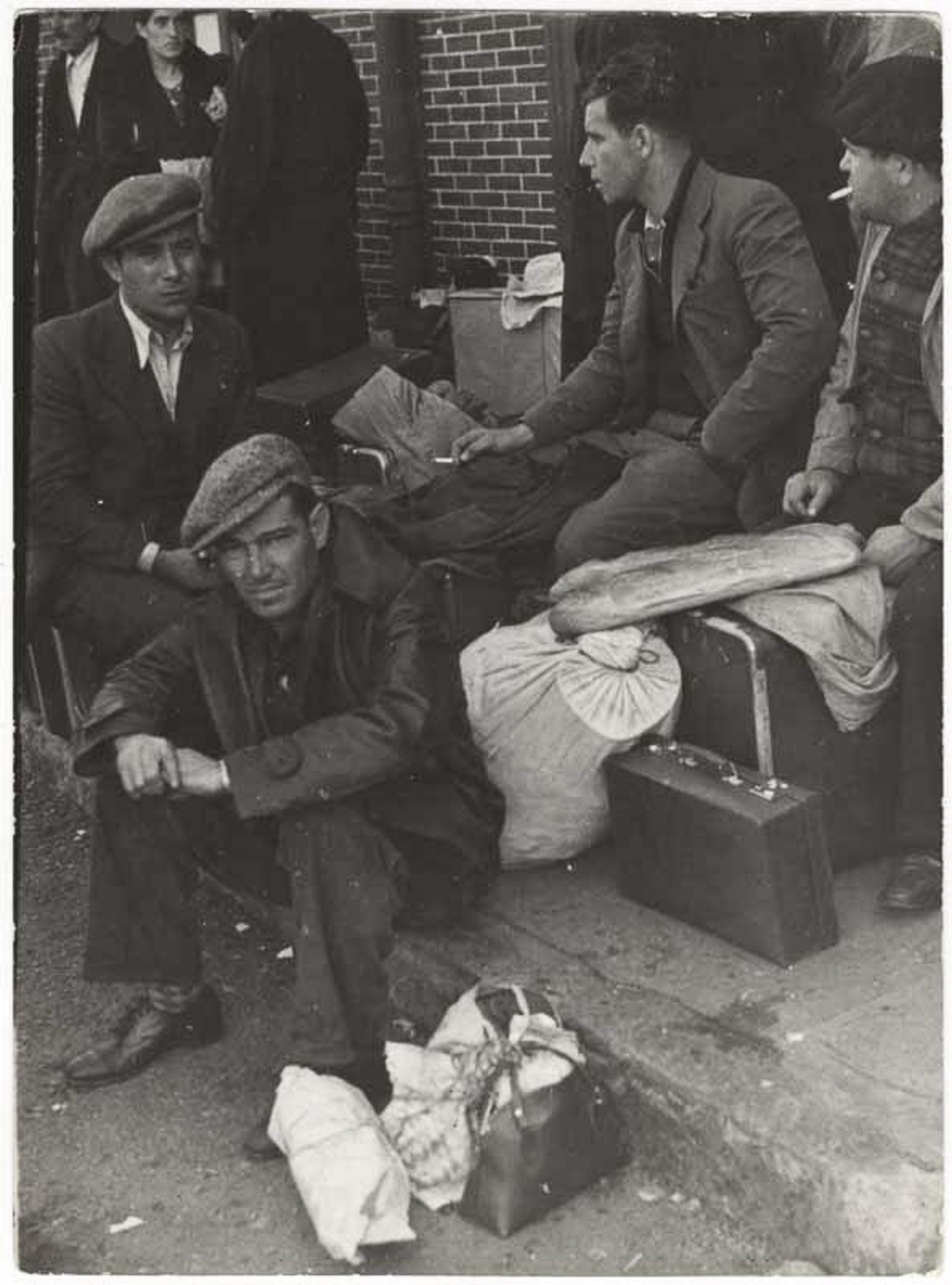 [Spanish refugees, mostly men wearing caps, sitting on suit cases and ...
