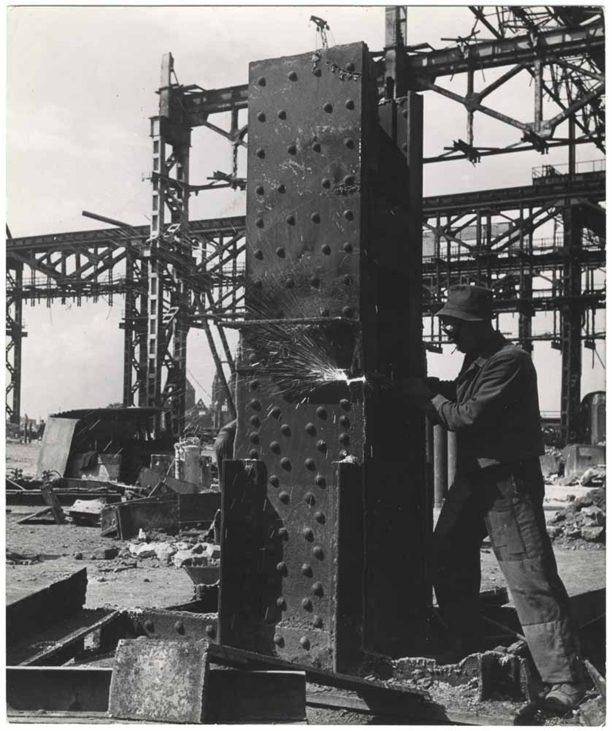 [Worker cutting metal, and smoking cigarette, in a partially destroyed ...