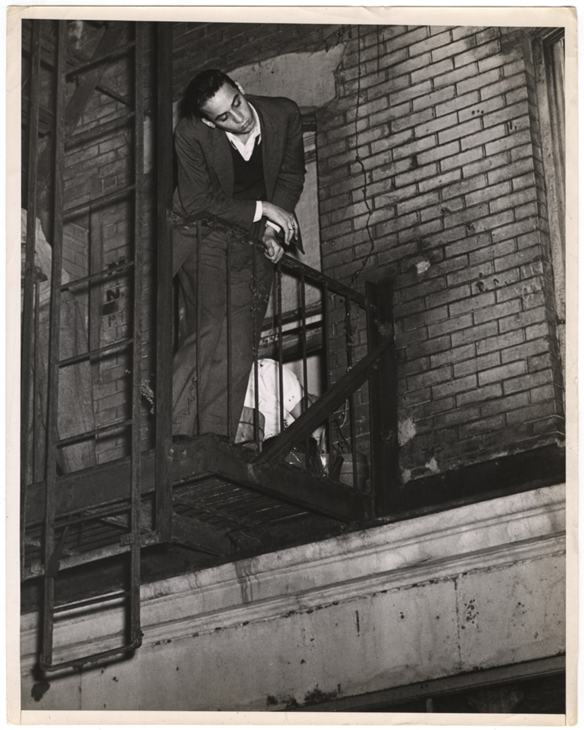 [Man on fire escape looking down] | International Center of Photography