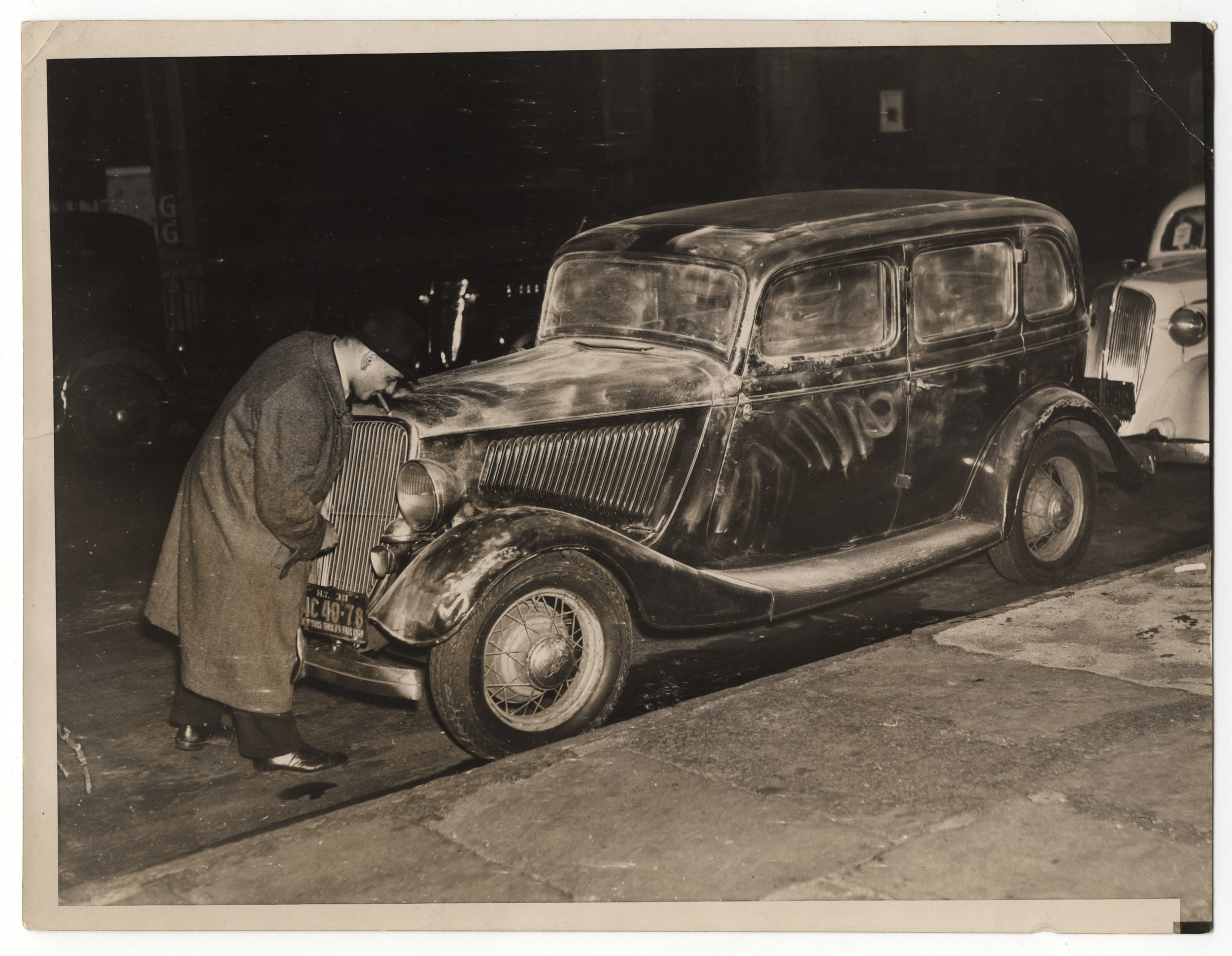 [Weegee looking at car] | International Center of Photography