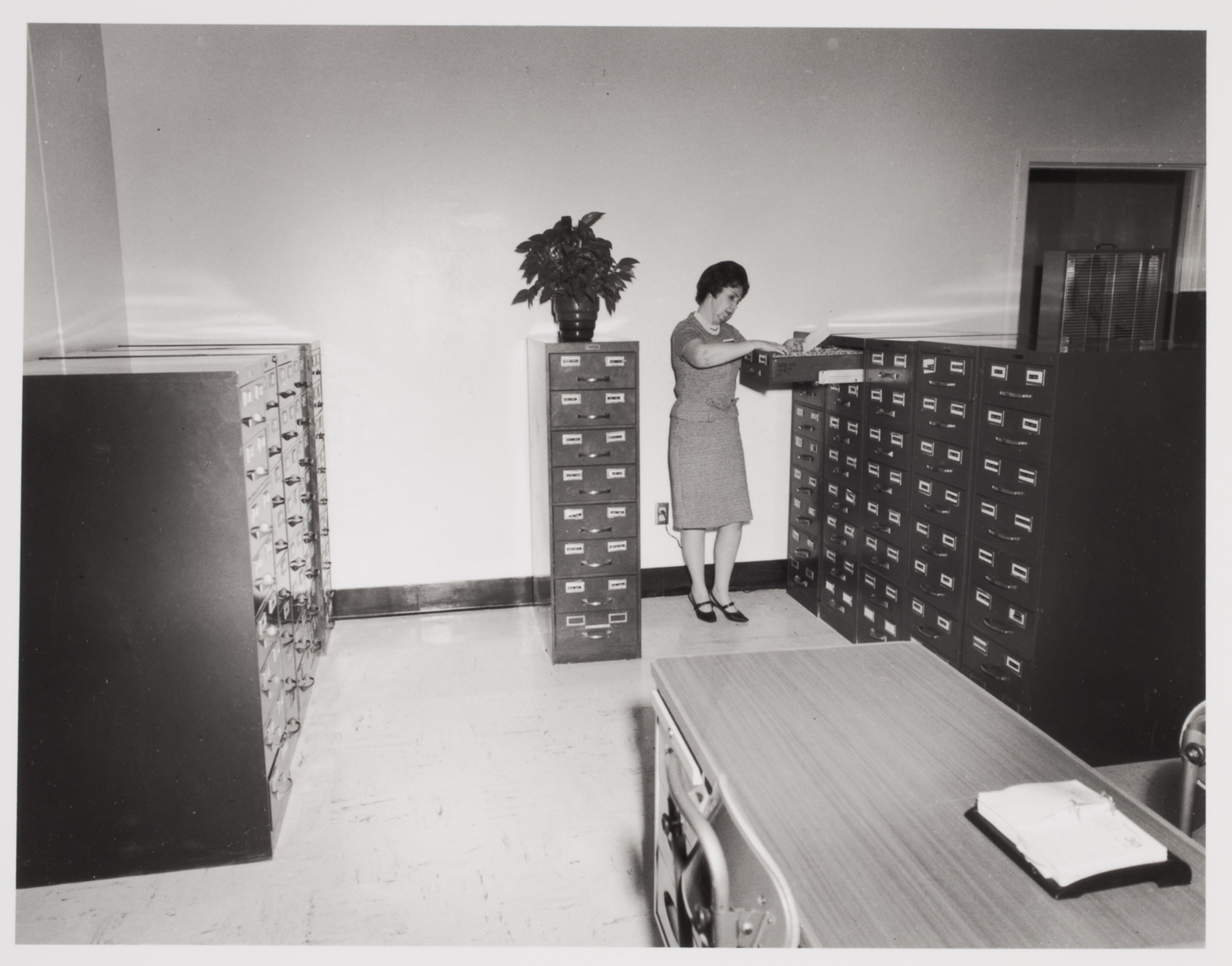 [Woman looking at filing cabinet] | International Center of Photography