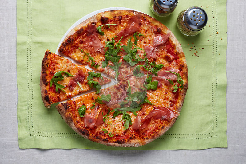 Gourmet wood fired proscuitto and arugula pizza photographed from above ...