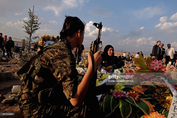 A YPJ fighter and relatives of fallen YPG fighters at the cemetery for ...