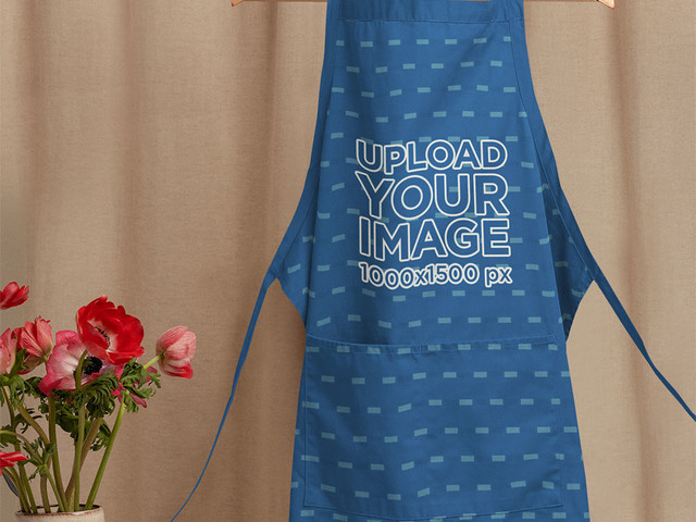 Placeit - Mockup of an Artist's Apron on a Hanger Behind a Work Table