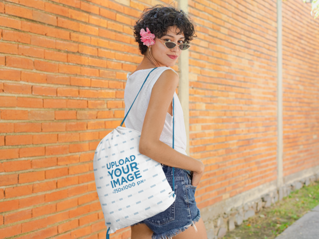Placeit - Drawstring Mockup Featuring a Woman With a Brick Wall Background