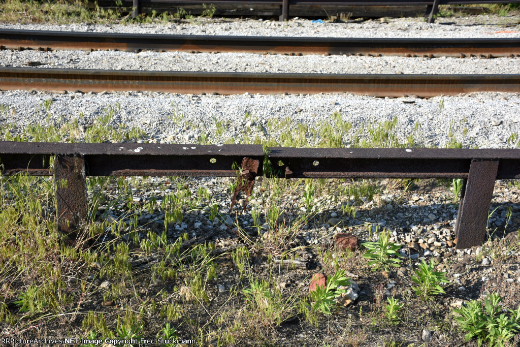 Inverted rail with a rusty angle iron still attached.