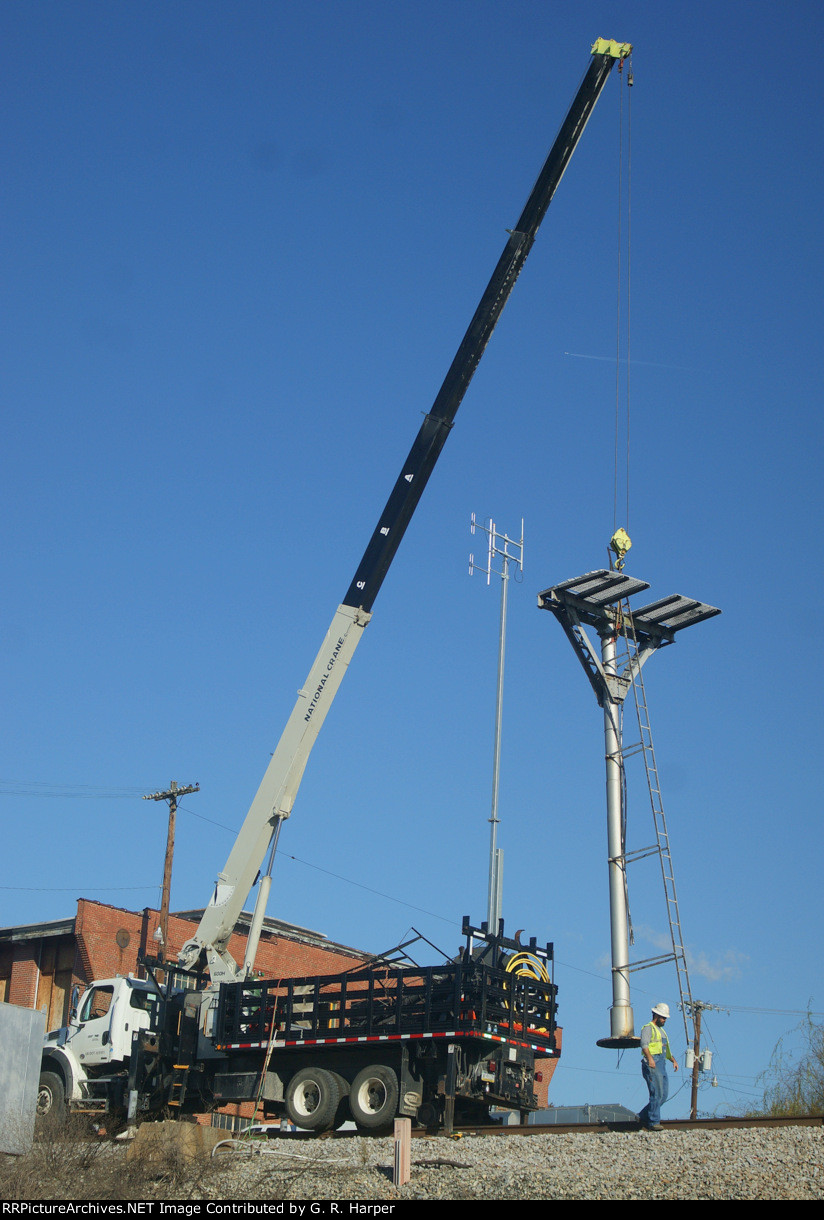 Headless signal mast is moved into position to be lowered.