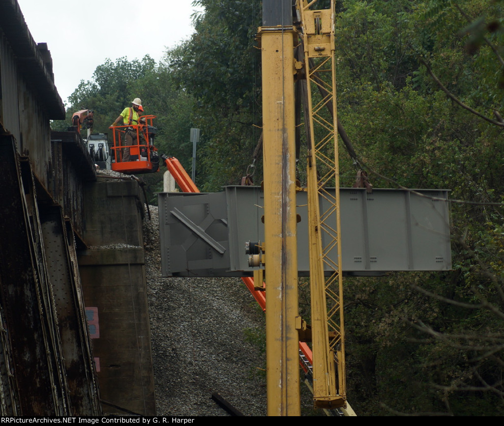 Broadside of new deck span being hoisted up.